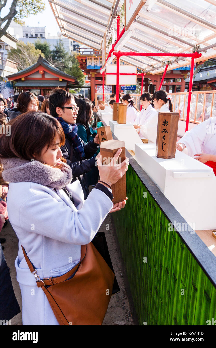 Japan, Kobe, Ikuta shrine. New Year. Young woman holding with both hands a wooden omikuji box to ...