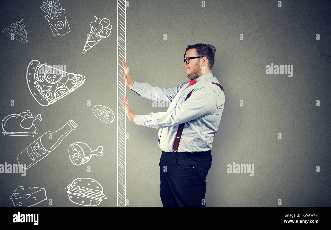 Side view of chunky man resisting temptation of eating fast foot and ...