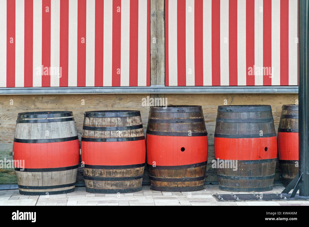 Wine barrels with a red border, standing against a wall with white-red ...