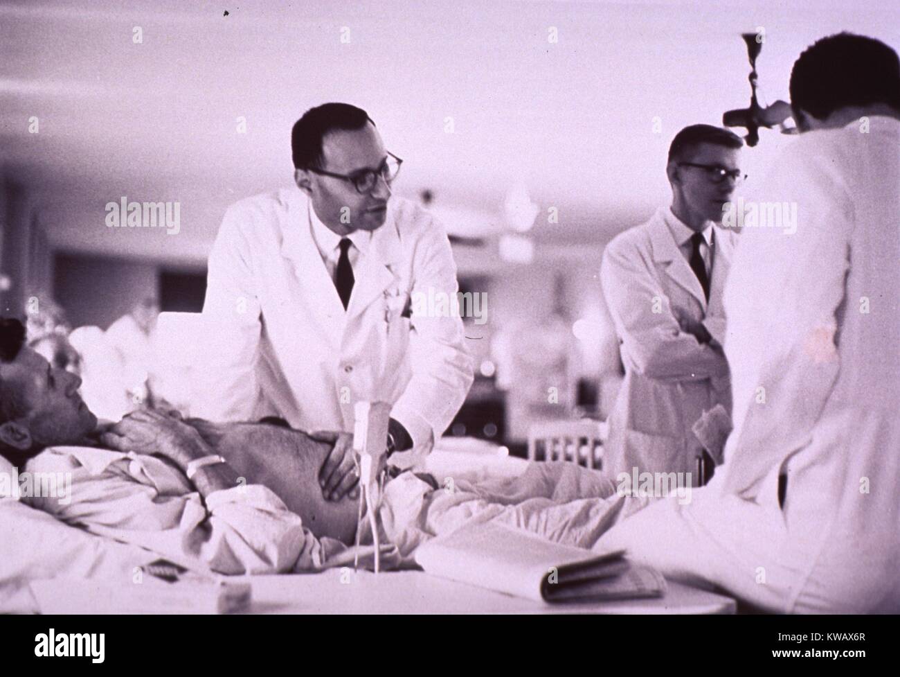 Physician applying pressure to a patient's left torso as two other ...
