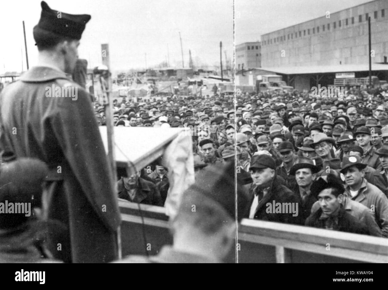 A figure addresses a large group of workers outside the Oak Ridge ...