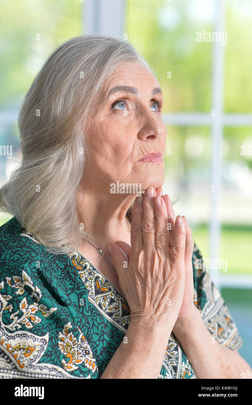 Portrait of a tired senior woman praying Stock Photo - Alamy