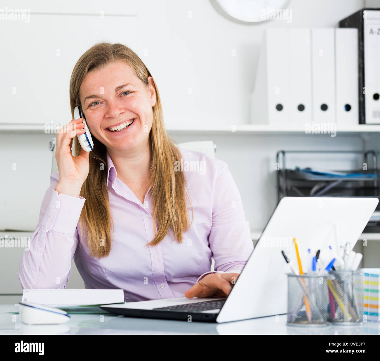 Female employee having conversation on phone during work Stock Photo ...