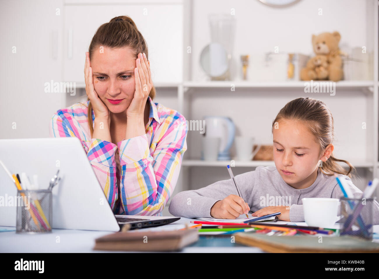 Portrait of sad female with little schoolgirl doing homewor Stock Photo ...