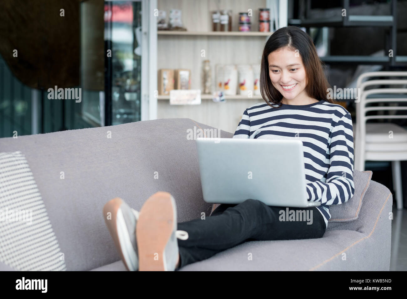 Asian teenager girl using laptop computer and sitting cross legs on ...
