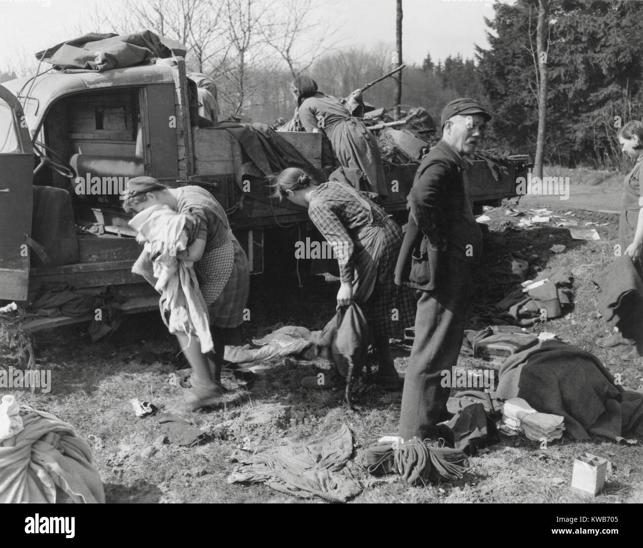 Civilians loot a knocked out German vehicle loaded with clothing and food. March 28, 1945 near ...