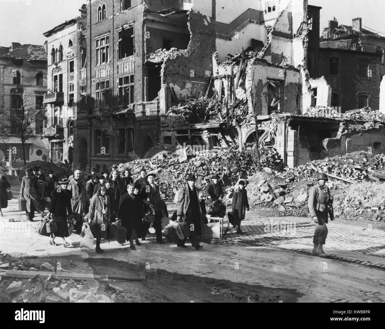 German civilians carry belongings as they follow an American soldier ...