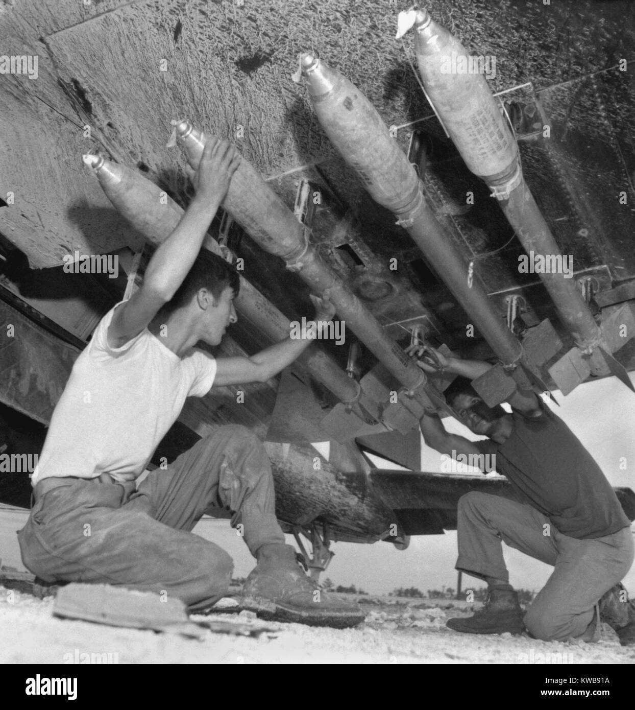 U.S. Marines load five-inch rockets under the wing of a Corsair fighter ...