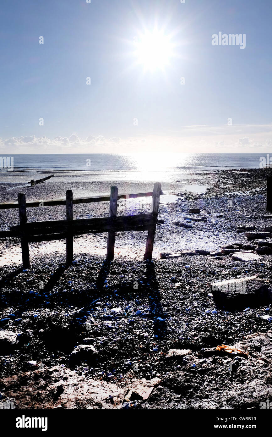 beach with rocks and pebbles and an old wooden big sea defence fence ...