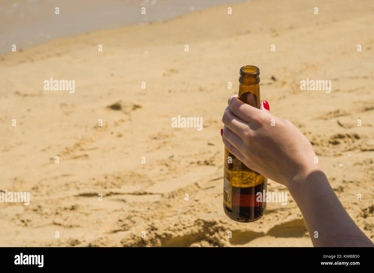 Woman hand with beer bottle in hand on beach Stock Photo - Alamy