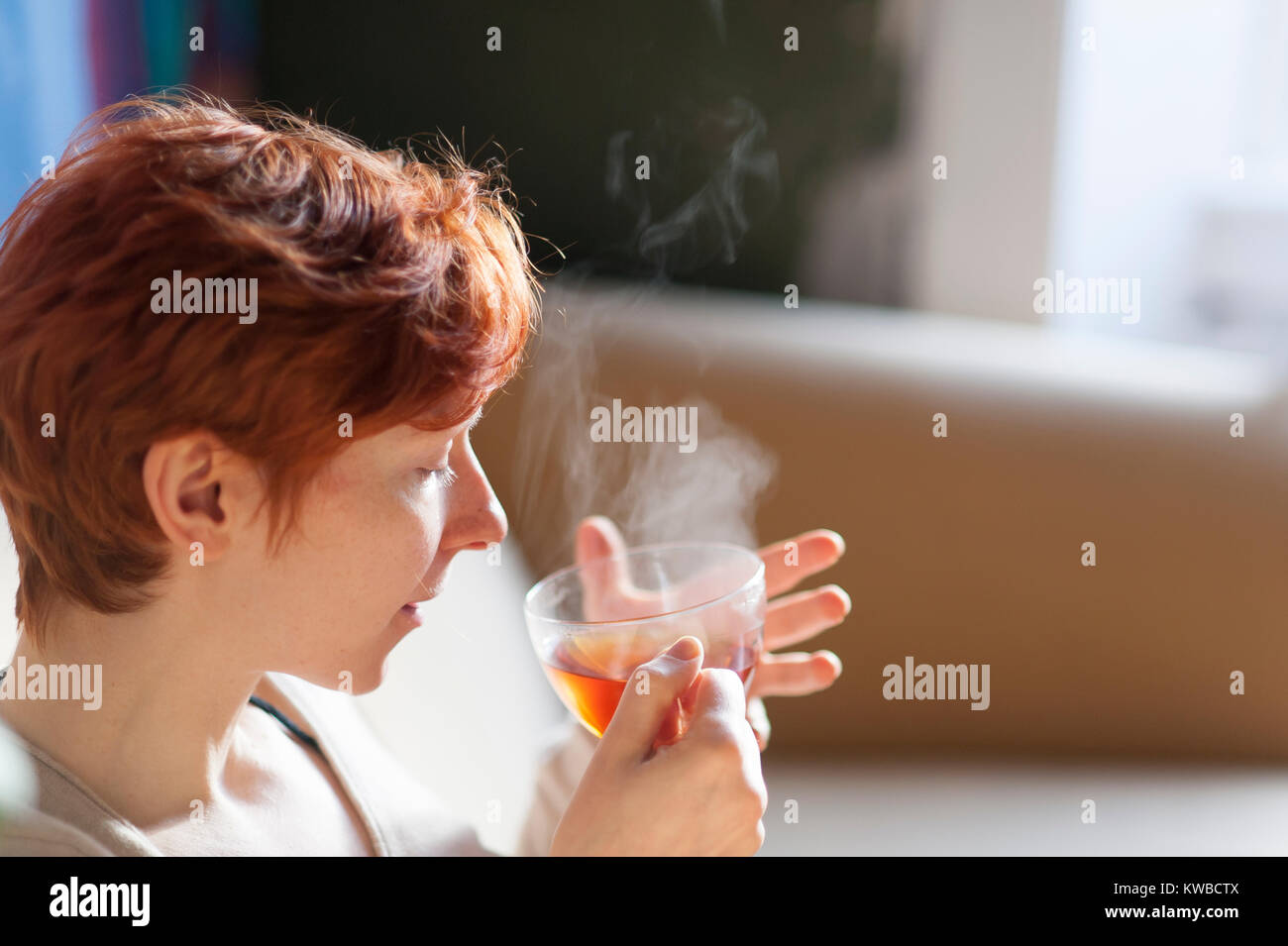 A woman drinking tea on sofa during a winter afternoon Stock Photo - Alamy