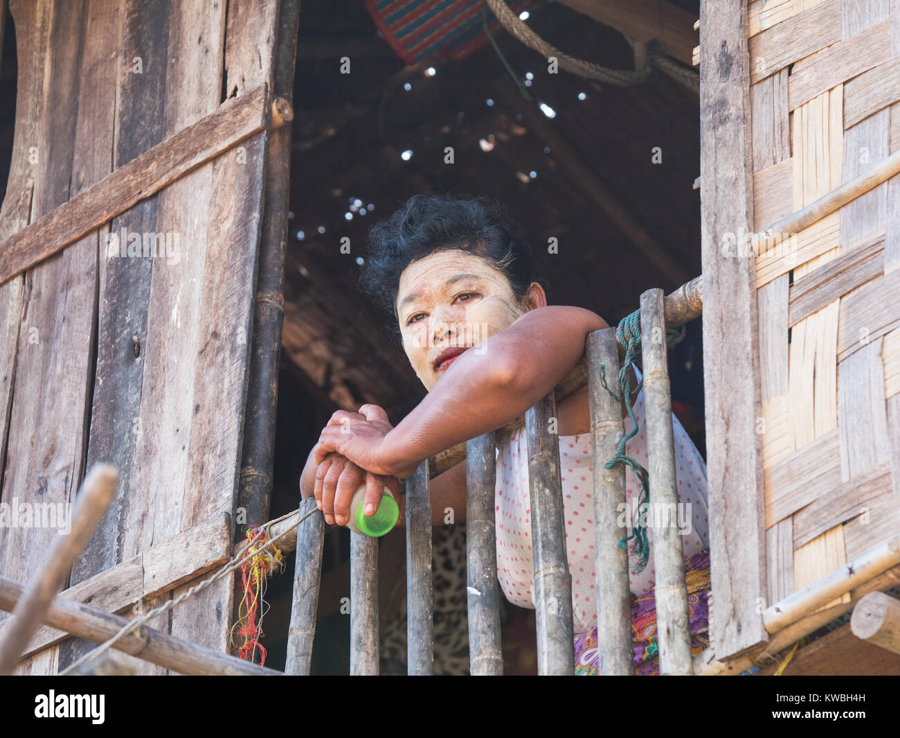 Woman with traditional tanaka in her face looking out from a fisherman ...
