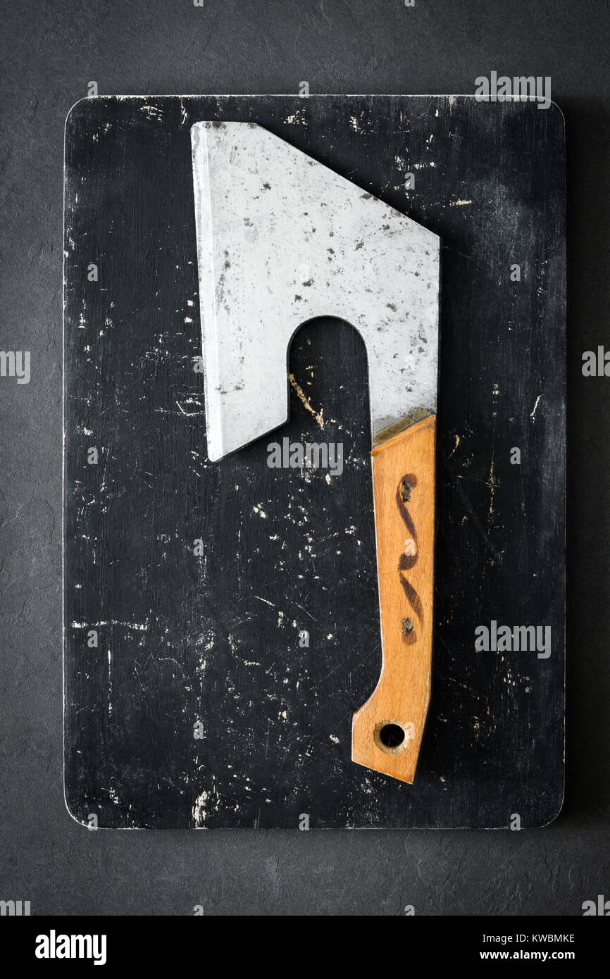 Old butcher axe or meat cleaver on black cutting board. Vertical, top ...