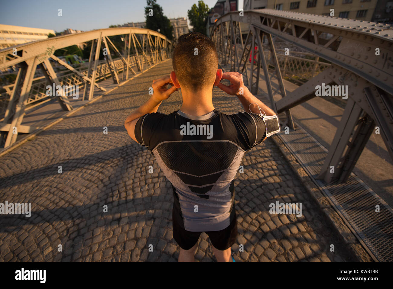 portrait of a young sporty jogging man at sunny morning in the city ...