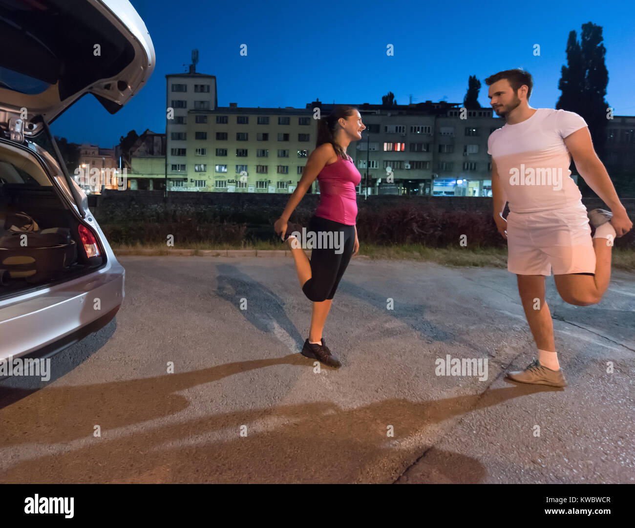 jogging couple warming up and stretching before evening running in the ...