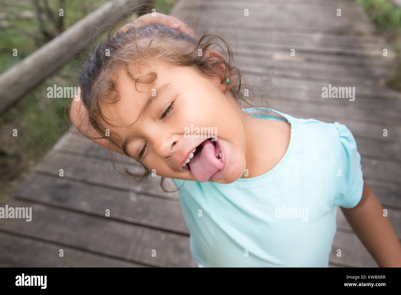 Portrait of cheerful little girl gesturing and making funny grimace at ...