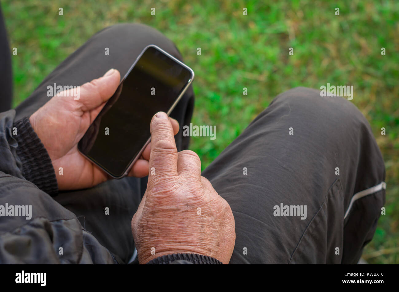 Close up of a wrinkled finger touching a smartphone, old man uses ...