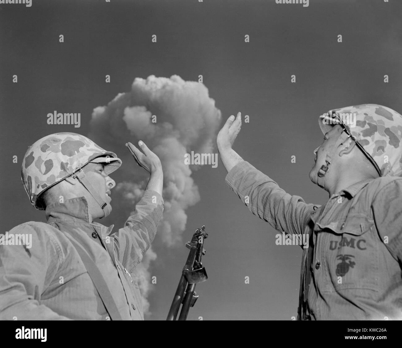 Soldiers pose below an atomic cloud at the Nevada Proving Ground ...