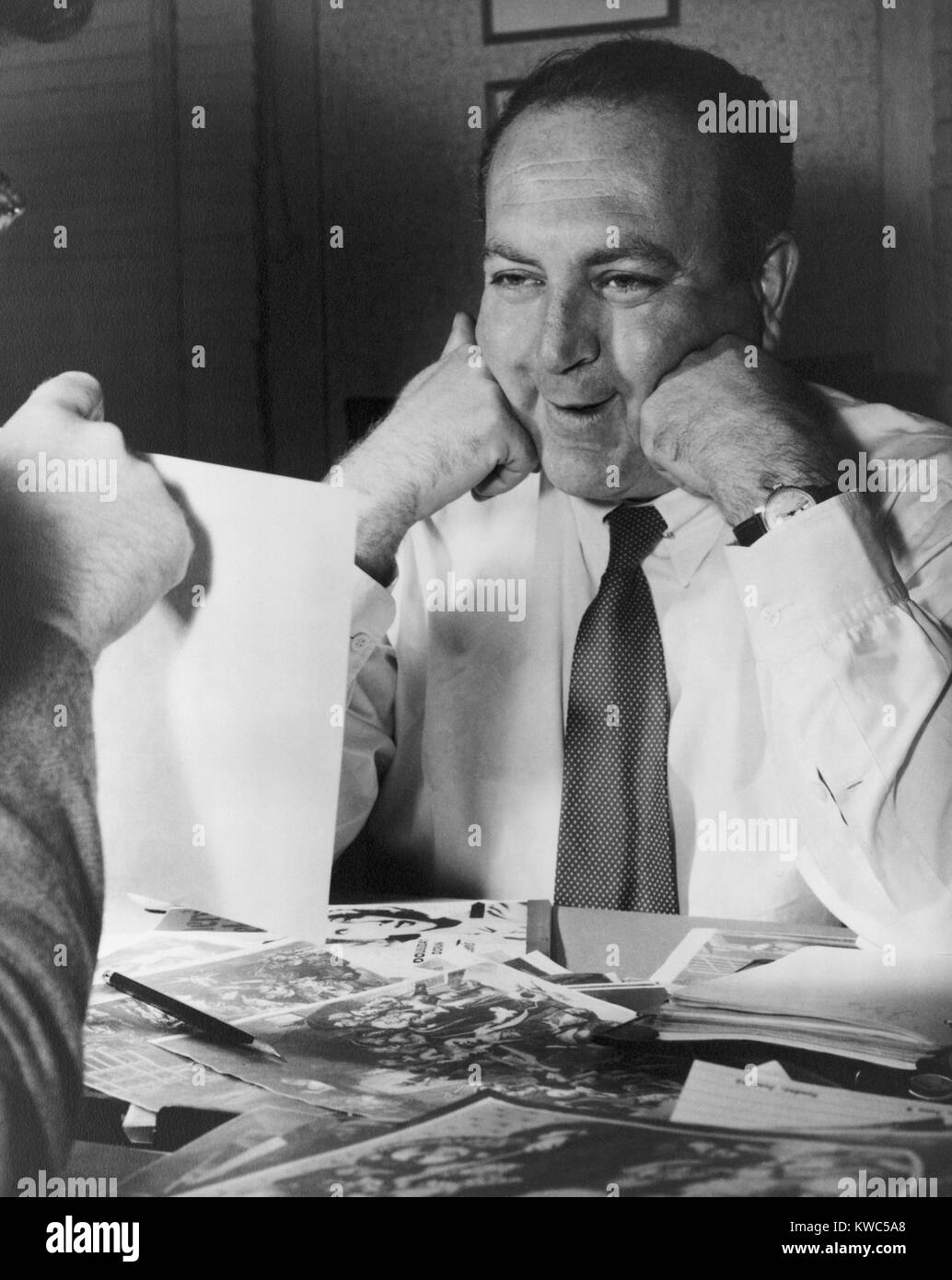 Film producer Val Lewton smiling as he looks at a photograph, in the ...