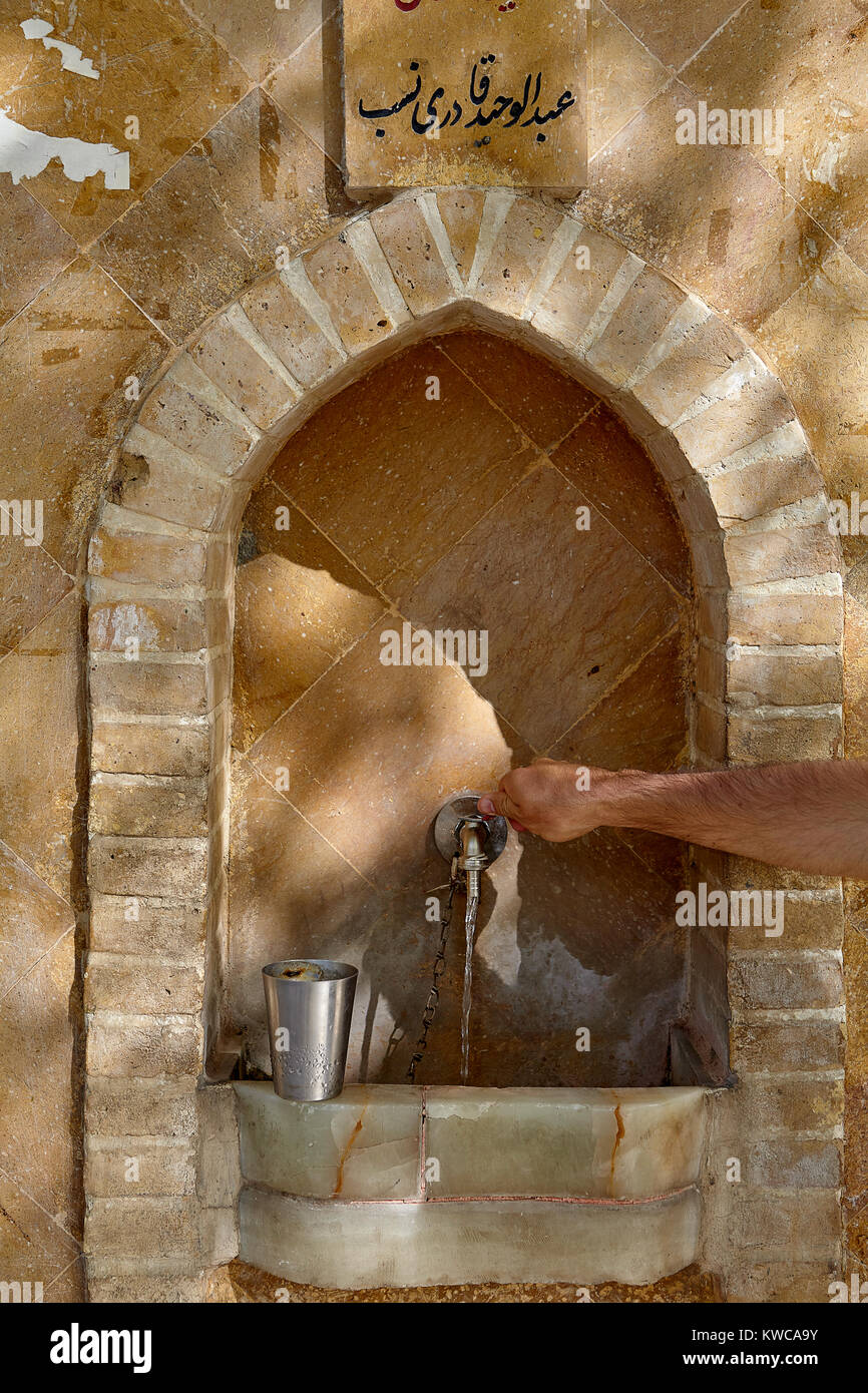 A human hand opens a public water tap with clean drinking water in the ...