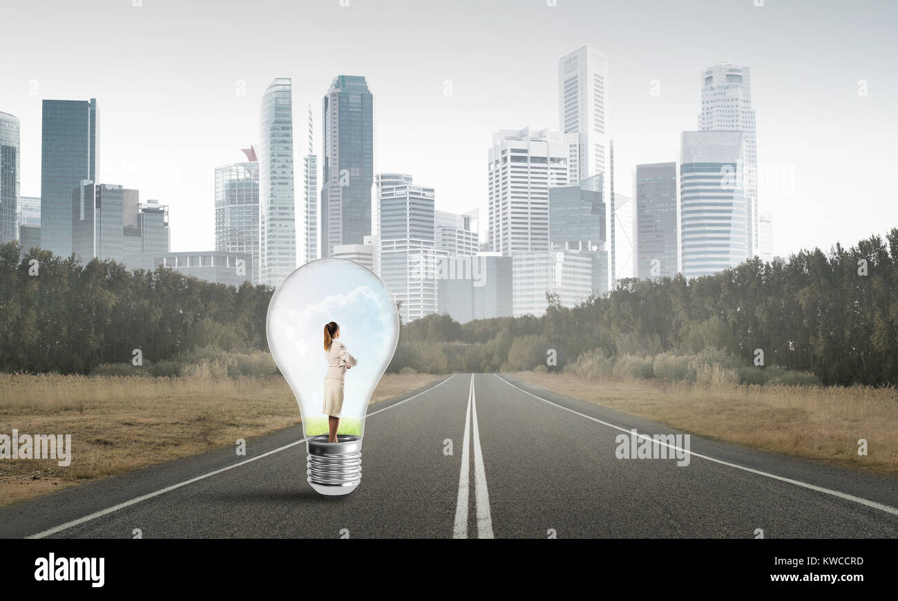 Young businesswoman trapped inside of light bulb on asphalt road Stock ...