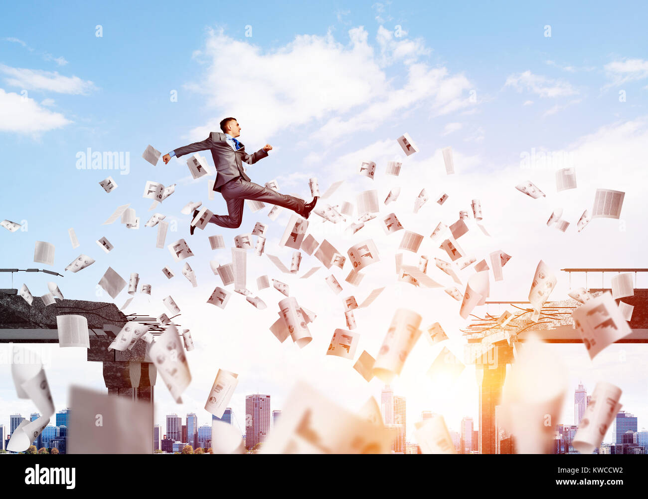 Businessman jumping over gap with flying paper documents in concrete ...