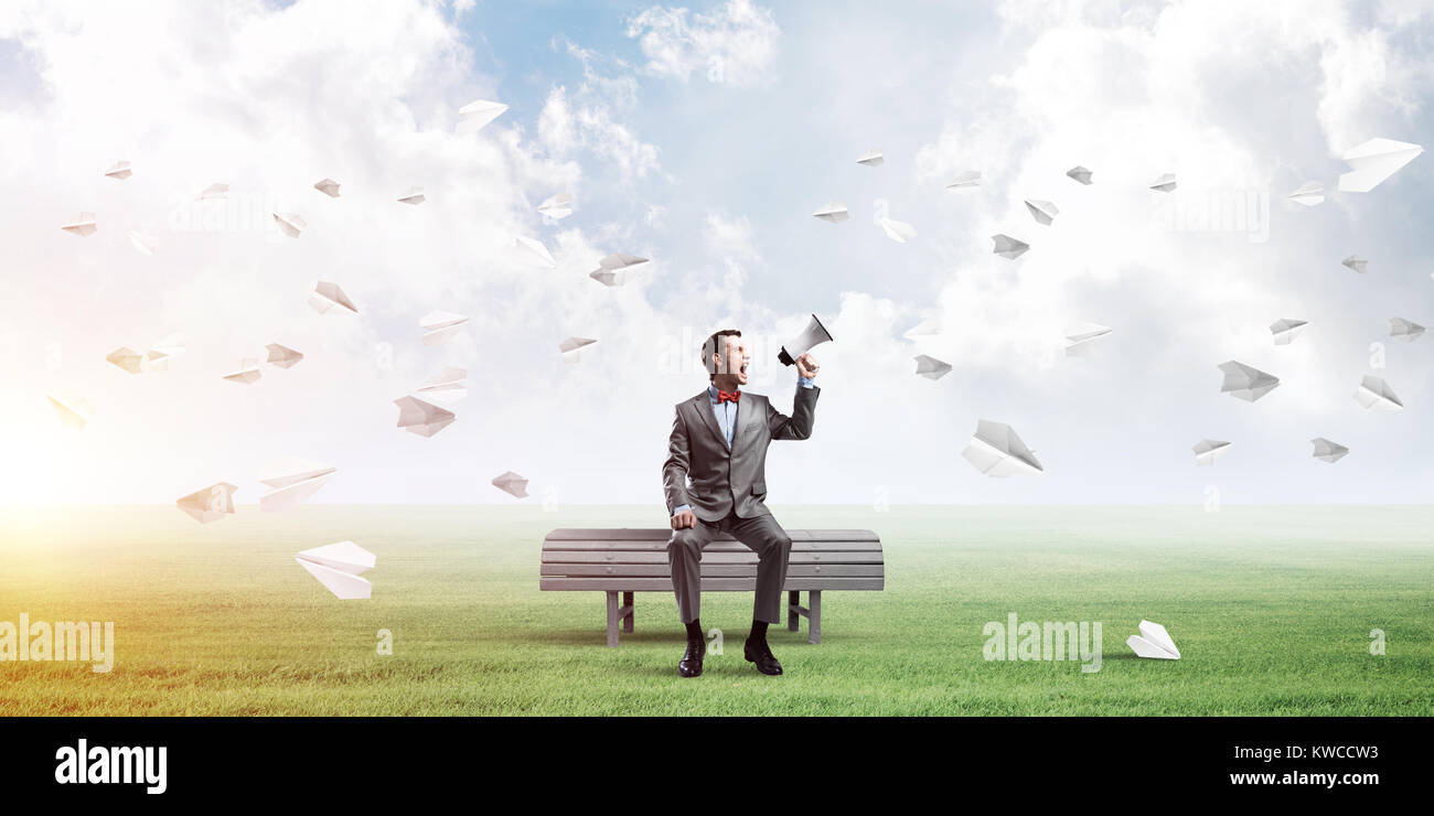 Young businessman sitting on bench and screaming emotionally in ...