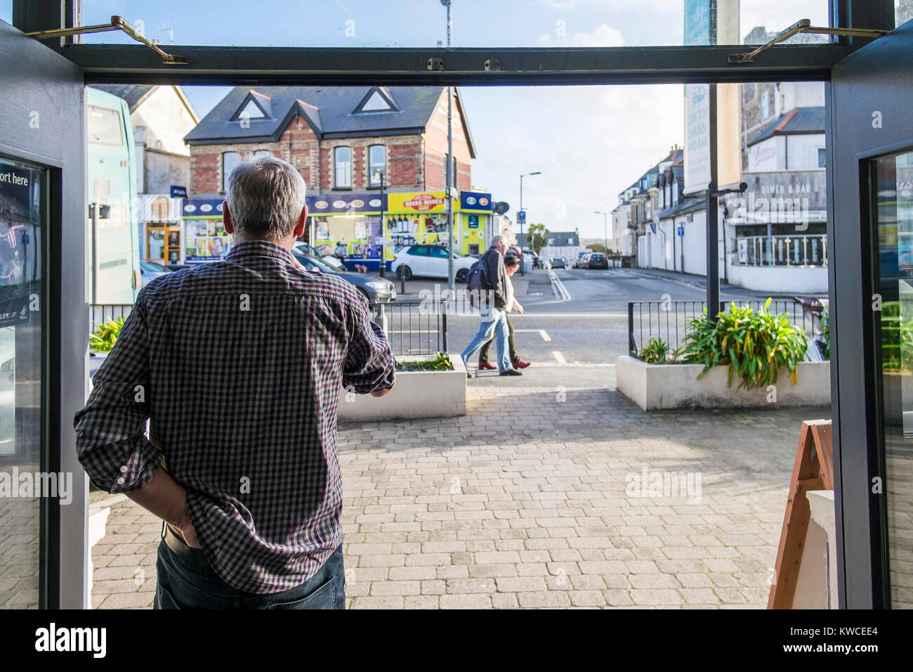 A man standing in a doorway looking out at a street in Newquay Cornwall ...