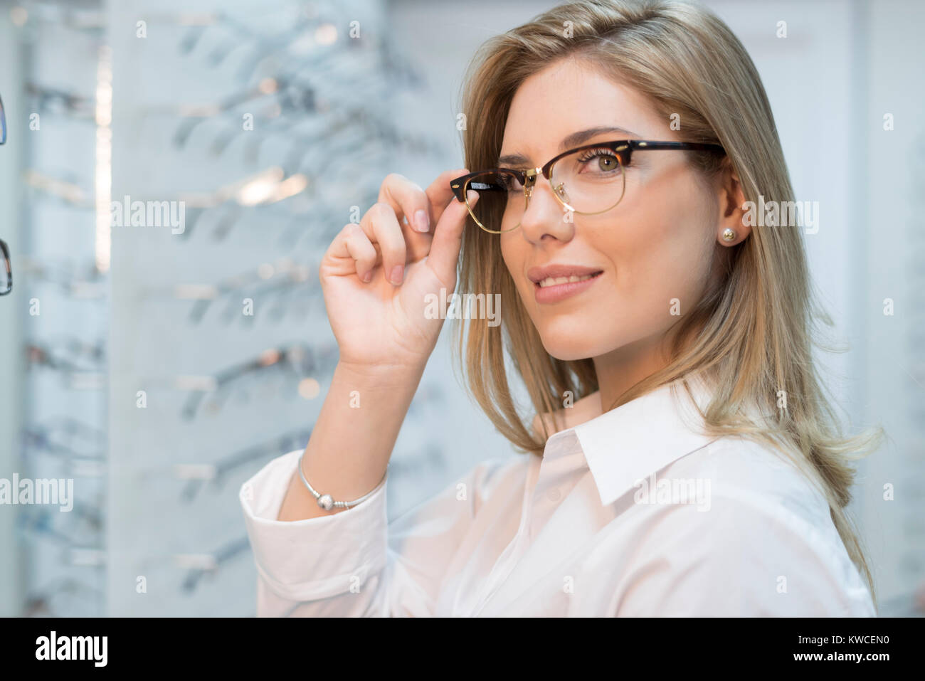 Woman trying on glasses in optical store Stock Photo - Alamy