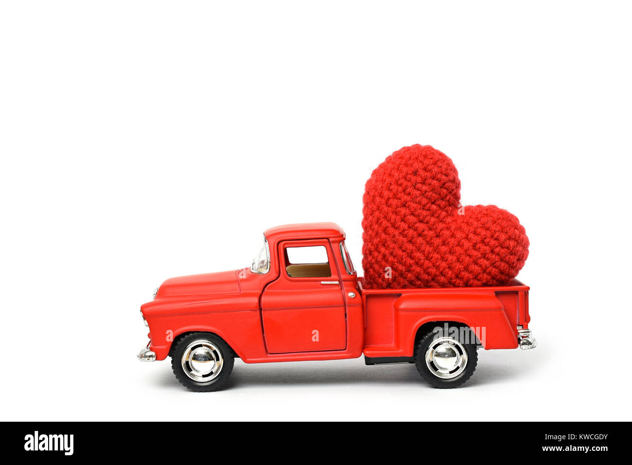 Red toy car delivering red heart for valentine's day on a white ...