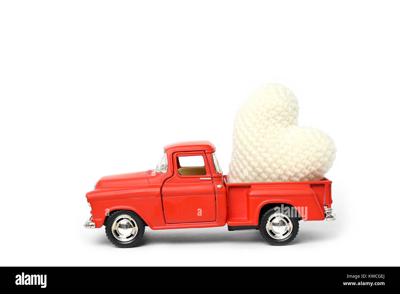 Red toy car delivering white heart for Valentine's day on a white ...