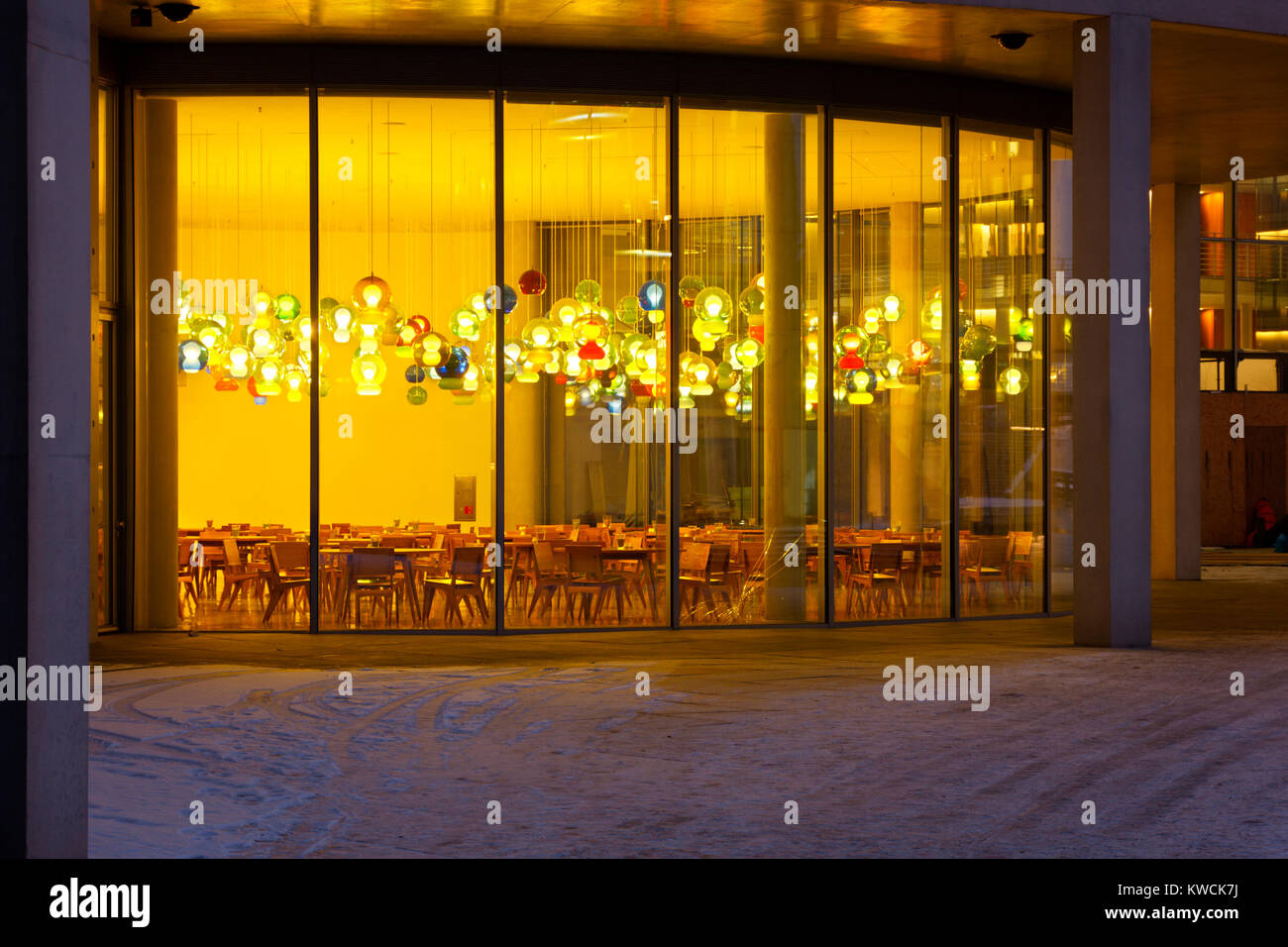View through a window into a room with lots of chairs and colorful ...