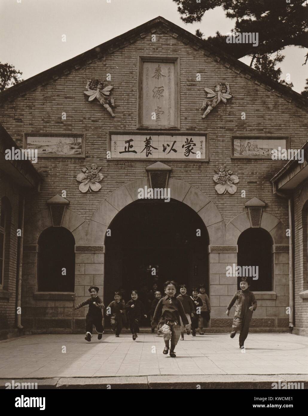 Children running out the entrance of a school building in China. The ...