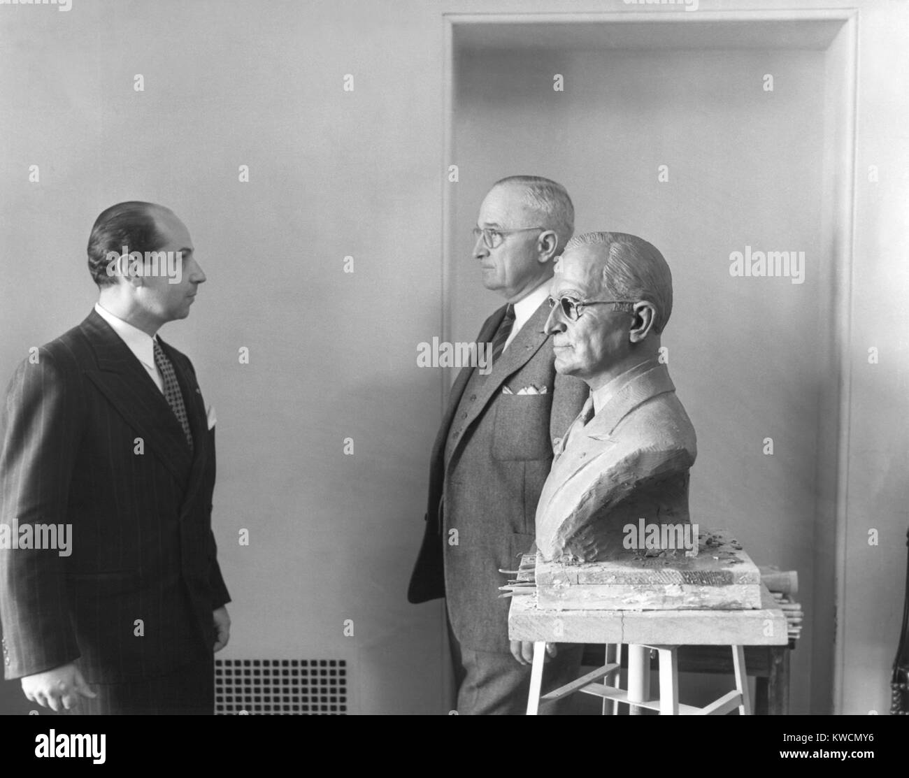 President Harry Truman poses next to the bust by artist Felix de Weldon ...