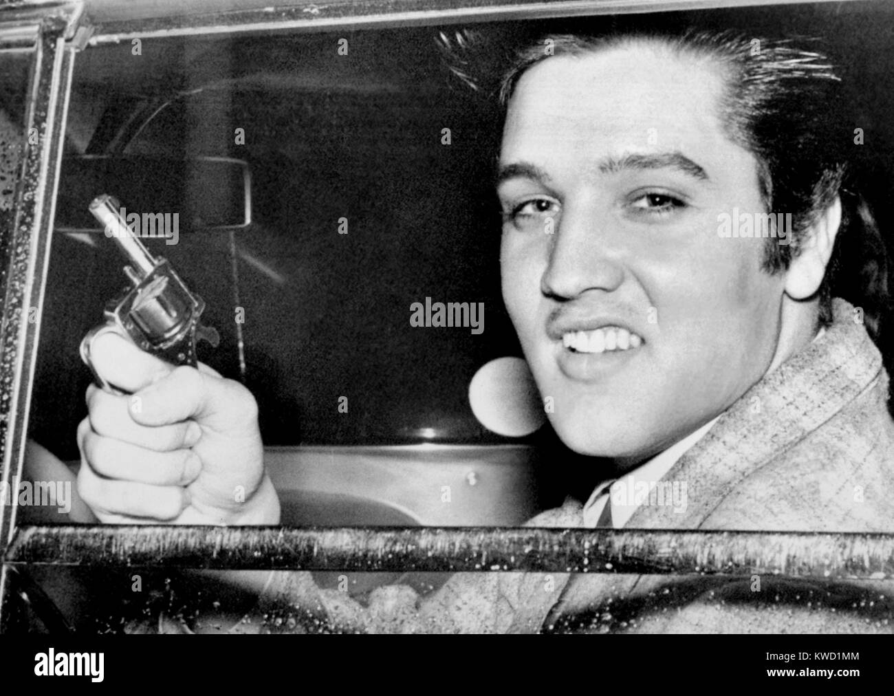 Elvis Presley holding the toy pistol he claimed he used in settling ...
