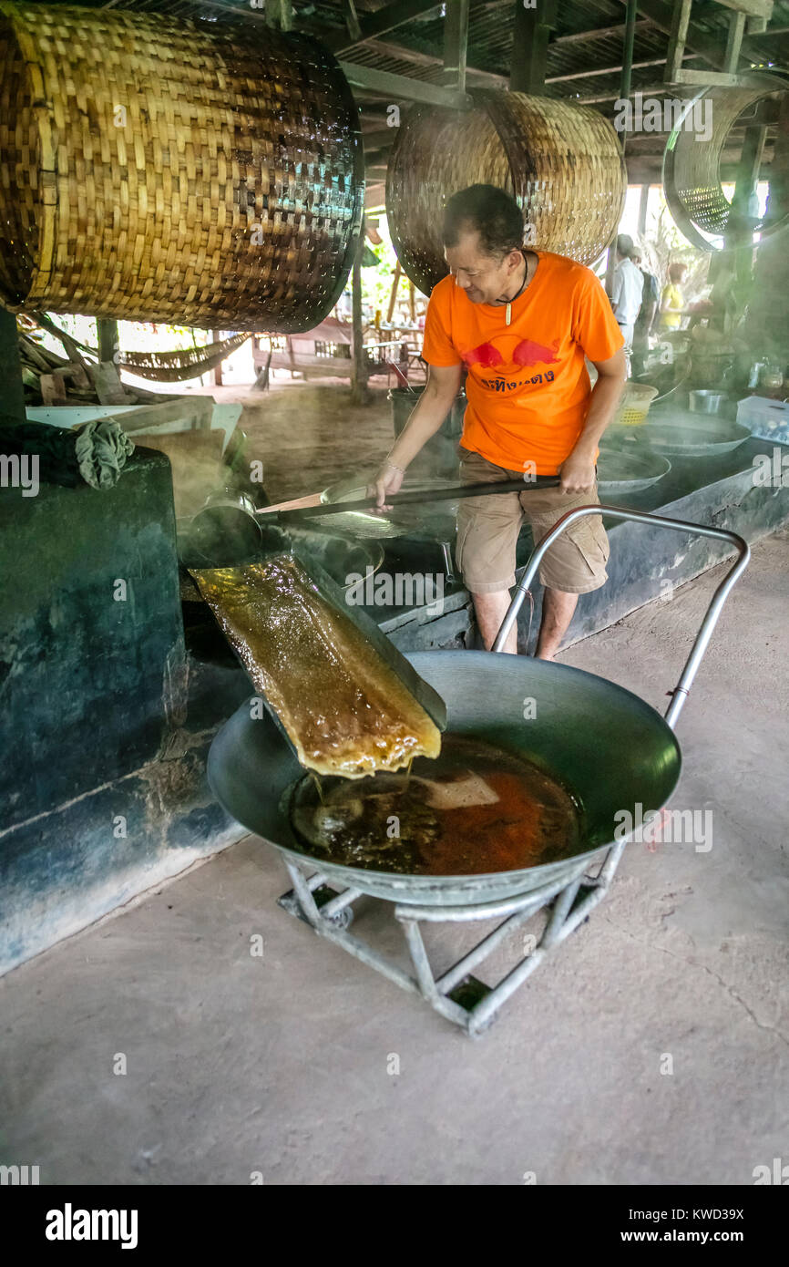 Thai worker removing evaporated coconut sugar sap syrup from heated ...