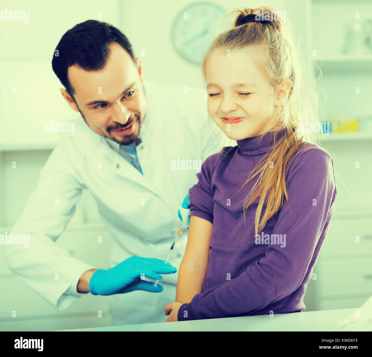 Male doctor using syringe to make injection to young female patient in ...