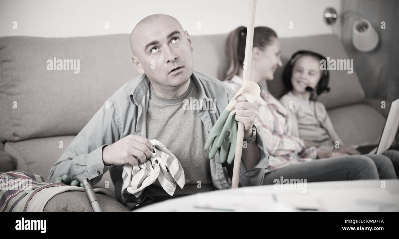 Tired father sitting near the table with mop after cleaning home Stock ...