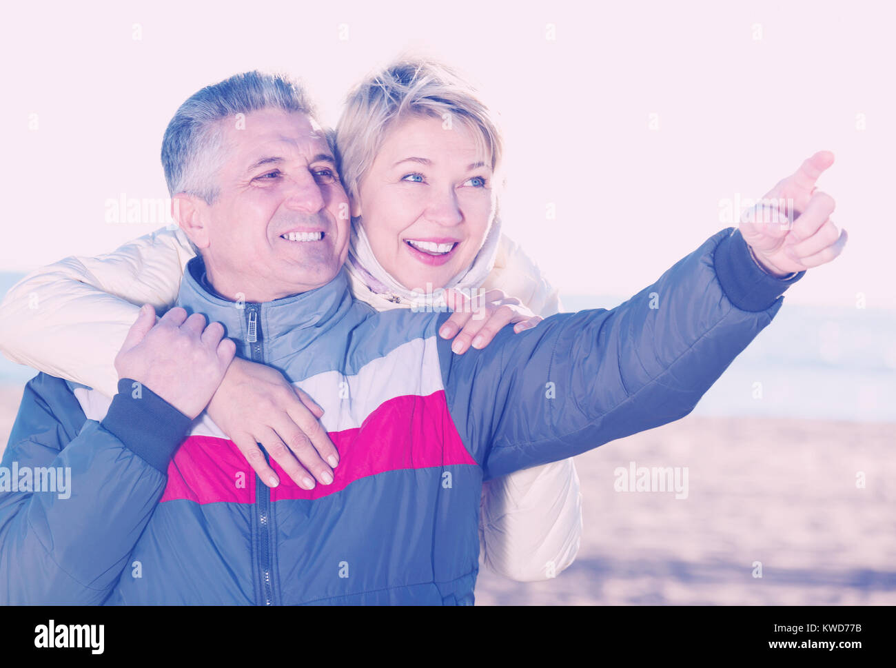 Adult married couple walk and husband points to wife to something ...