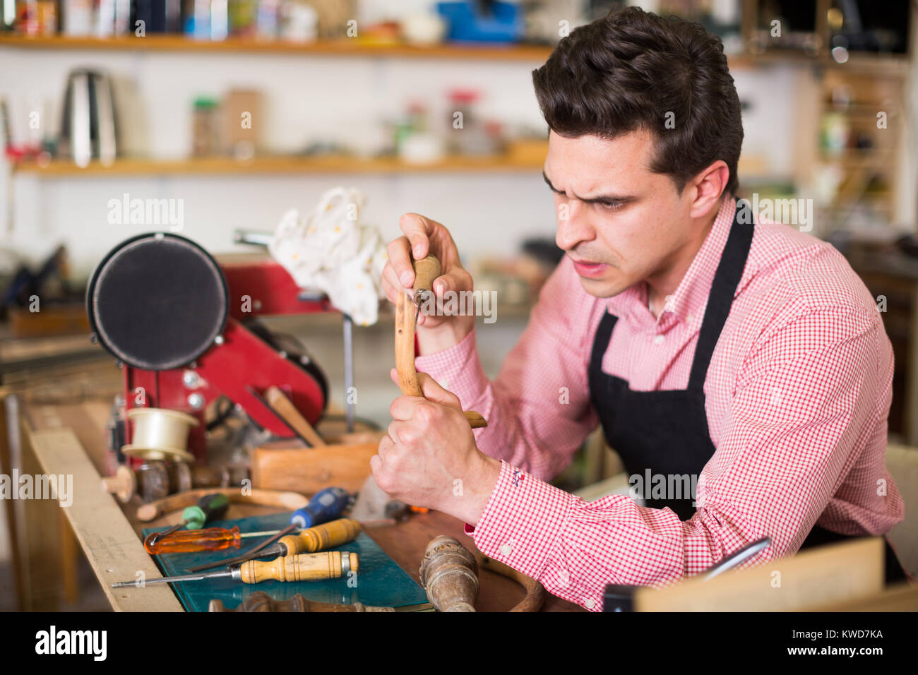 Skilled concentrated joiner working in workshop with chisel in hands ...