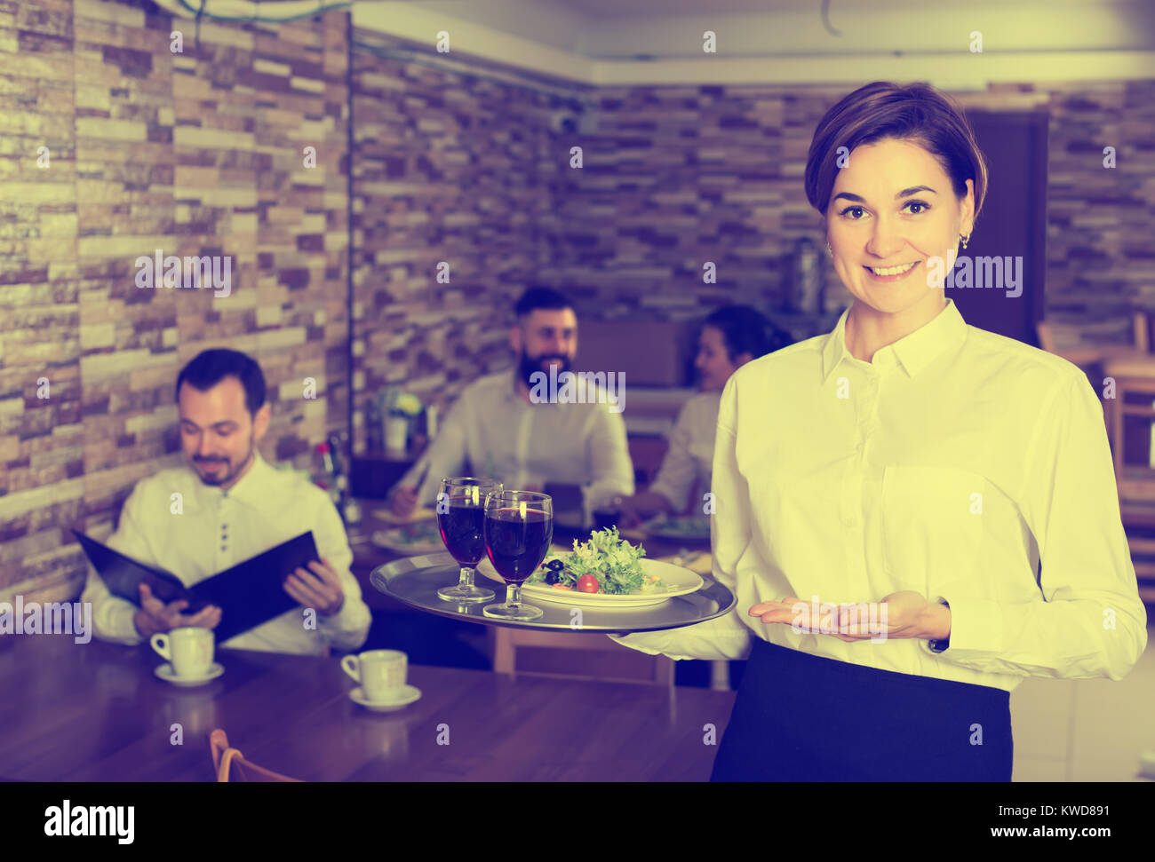 Charming young waitress greeting customers at table in cafe Stock Photo ...