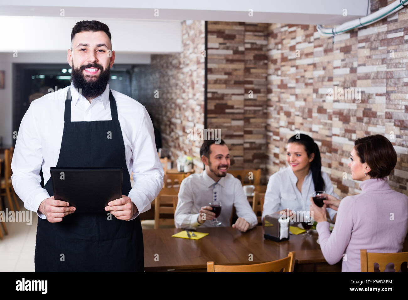 Positive waiter serving dear restaurant guests at table Stock Photo - Alamy