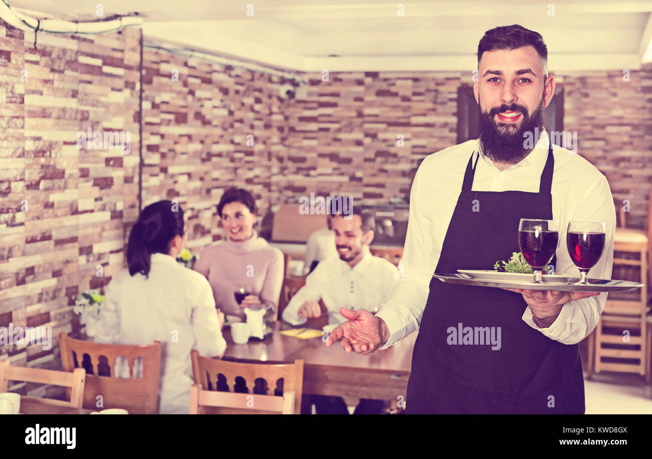 Cheerful waiter serving a rural restaurant guests at a table Stock ...