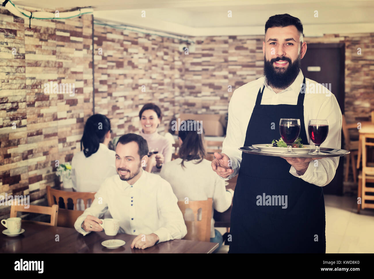 Cheerful male waiter serving rural restaurant guests at table Stock ...