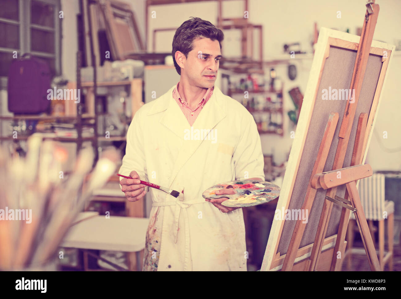 Happy art painter holding artist palette and painting on canvas Stock ...