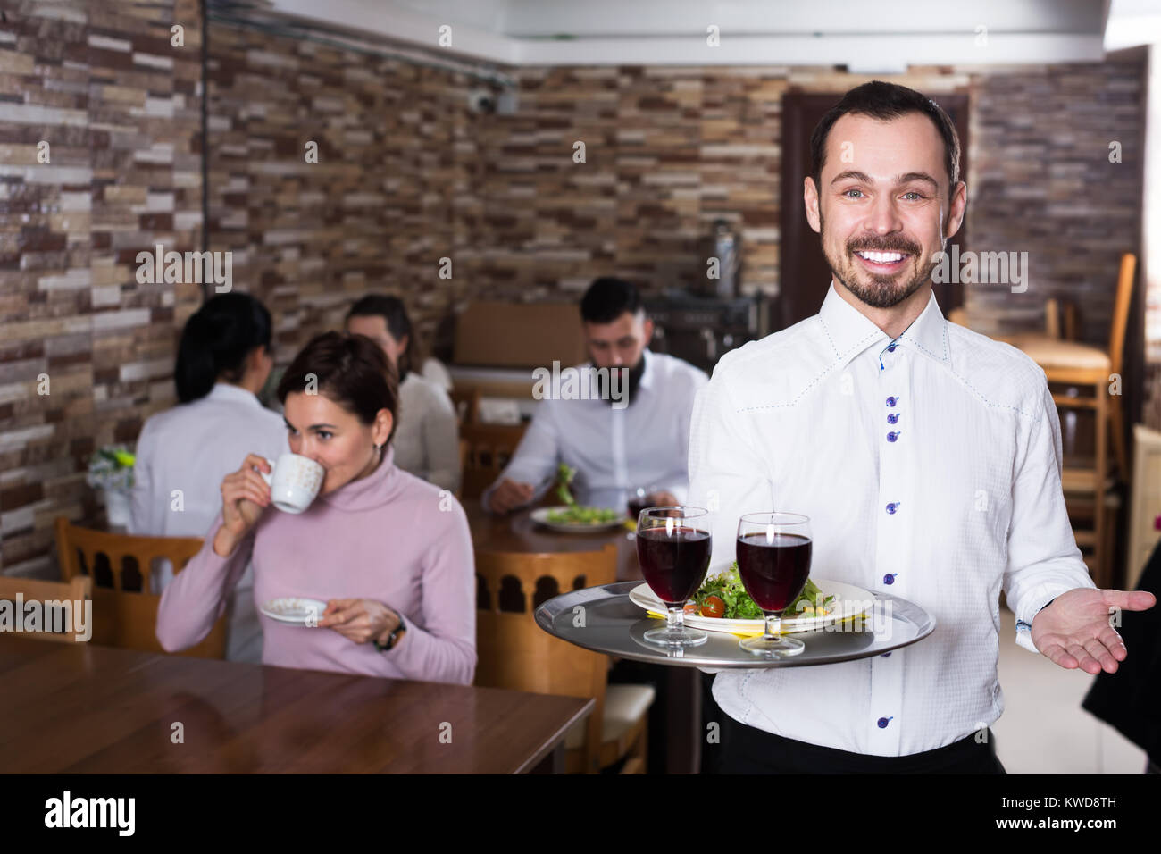 Young man waiter demonstrating rustic restaurant to visitors Stock ...
