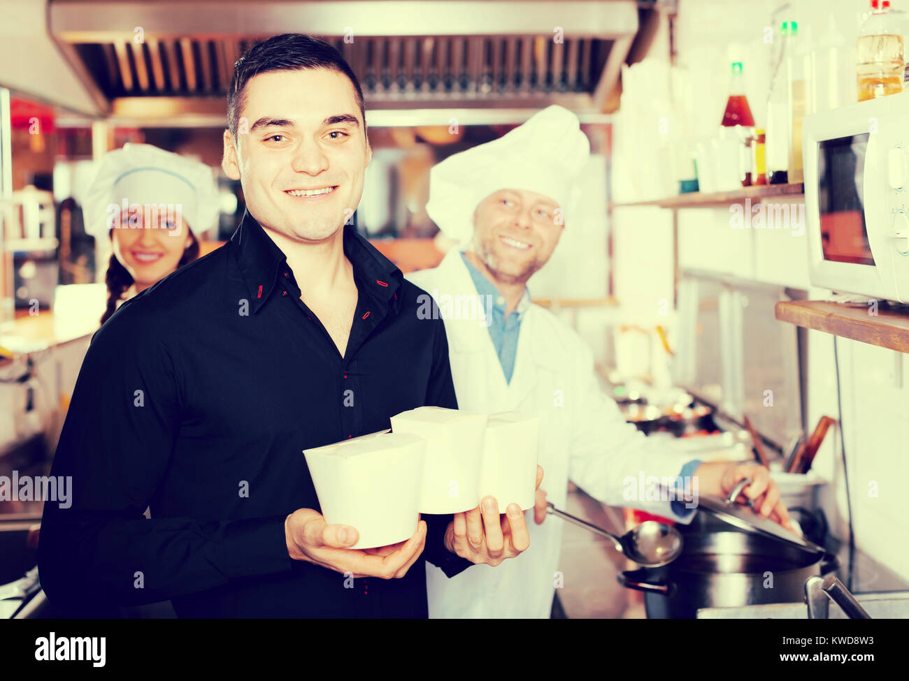 Portrait smiling young client and cooks buying take-away food at eating ...