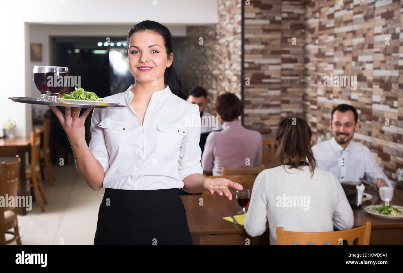 Hard-working waitress greeting customers at table in cafe Stock Photo ...