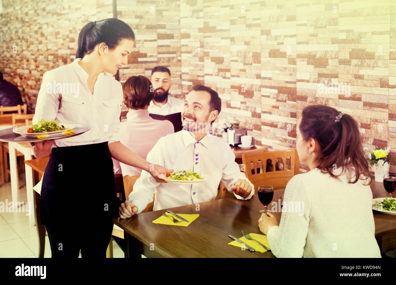 Positive waitress taking table order and smiling at tavern Stock Photo ...