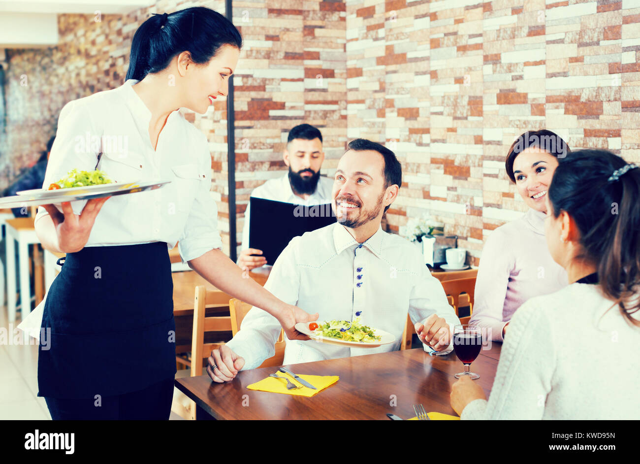 Positive waitress taking table order and smiling in the tavern Stock ...